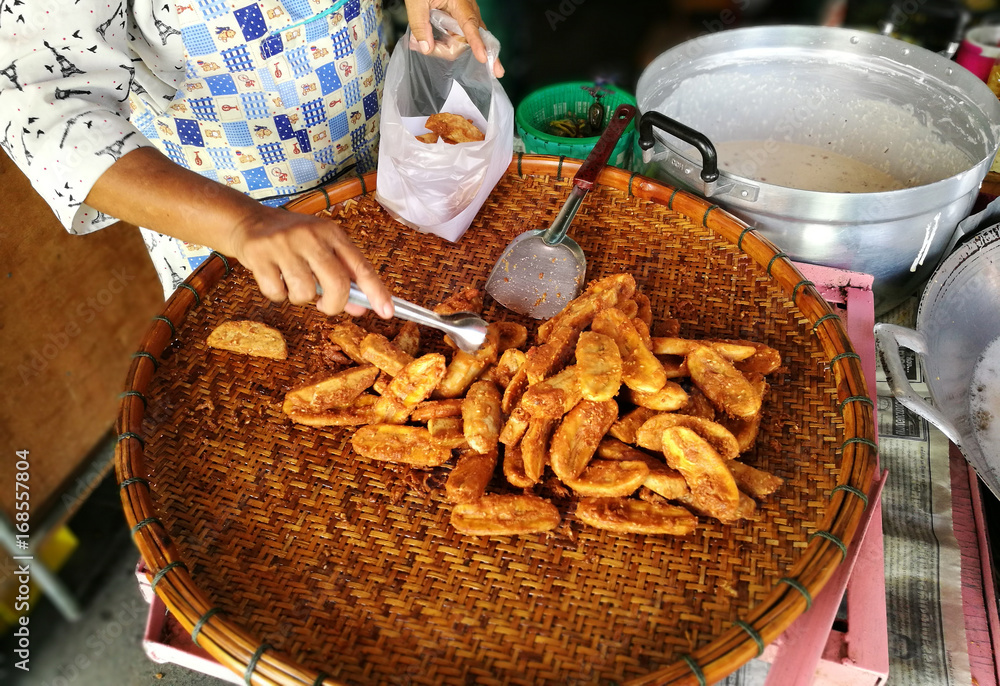 Street vendor picking Thai-styled fried banana recipe (kluay khaek or ...