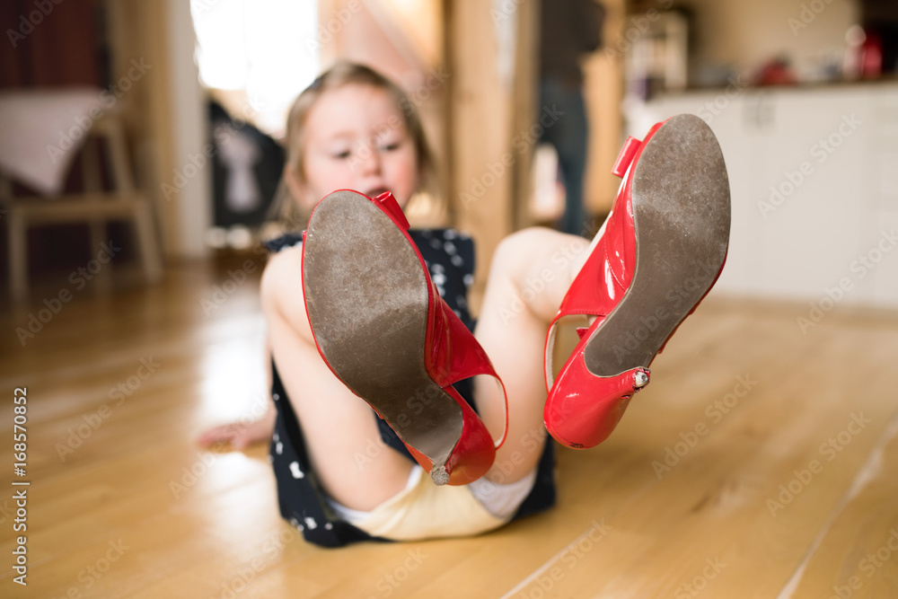 Little girl in dress and red high heels at home. Stock Photo | Adobe Stock