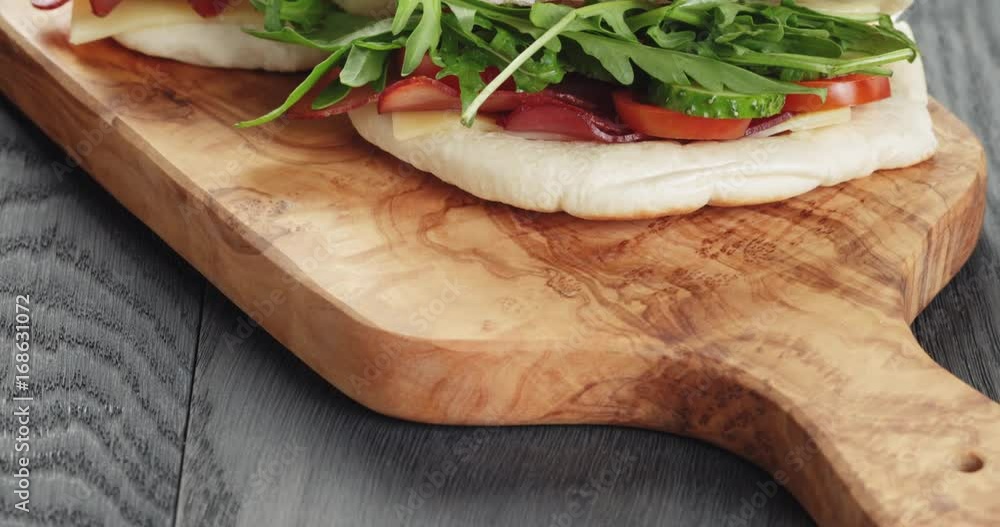 rustic sandwiches with ham arugula and tomatoes in pita bread, on wood ...
