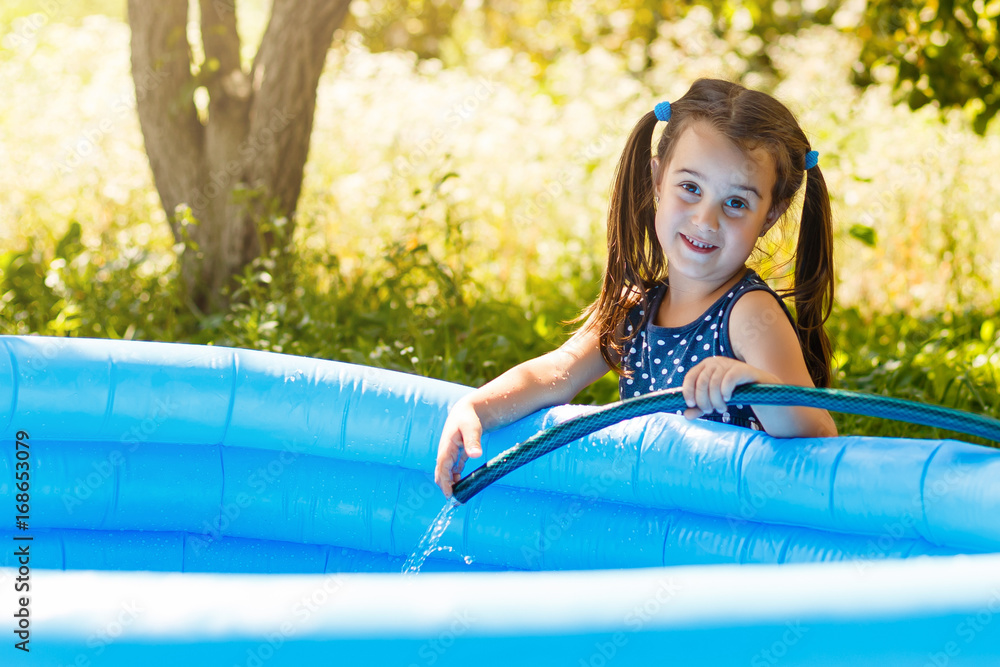Little girl pouring water into a small pool Stock Photo | Adobe Stock