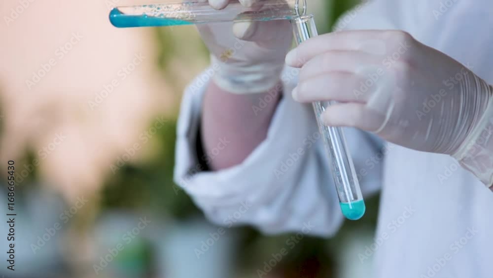 Scientist hand pouring a chemical solution from a laboratory glass test ...