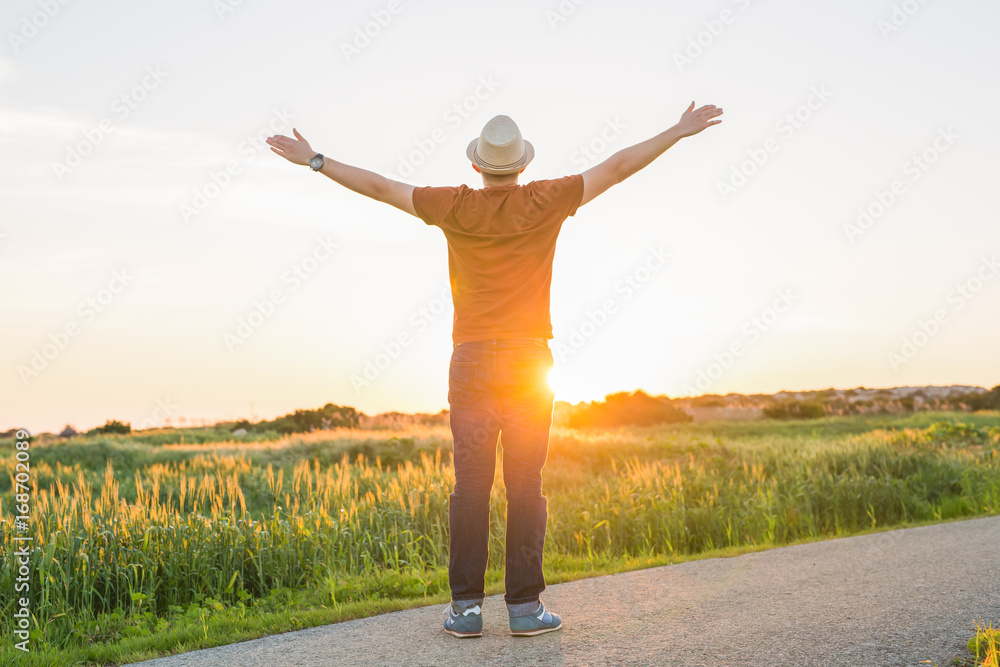 Man with arms raised, looking out over field Stock Photo | Adobe Stock