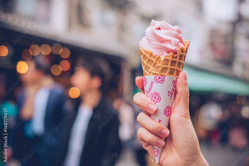 Woman Hand Holding Strawberry Waffle Ice Cream Cone On Bokeh Background