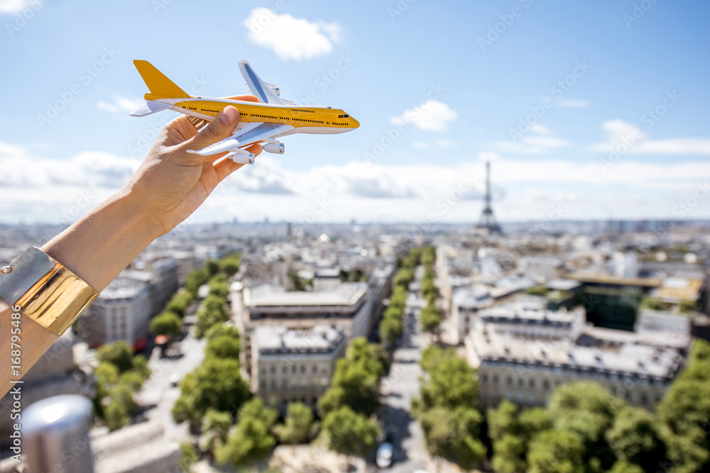 Holding a toy airplane on the Paris cityscape background. Air ...