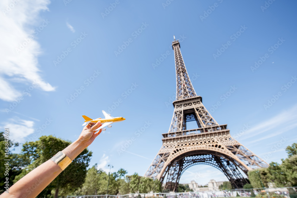 Holding a toy airplane on the Eiffel tower background. Air connection ...