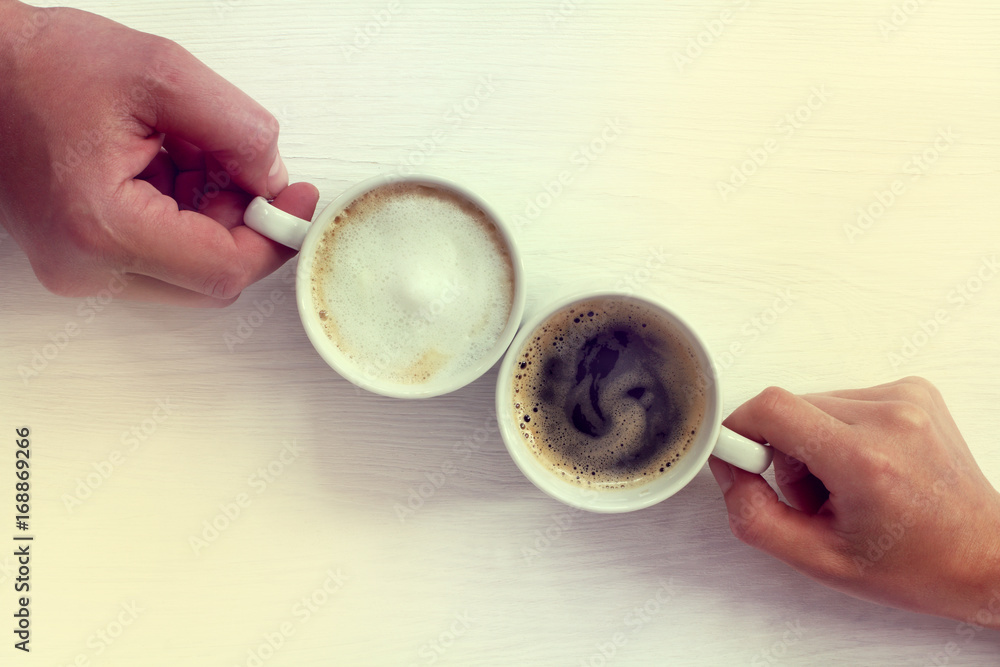 joint coffee break/ Two hands holding a cup with light and dark drink ...