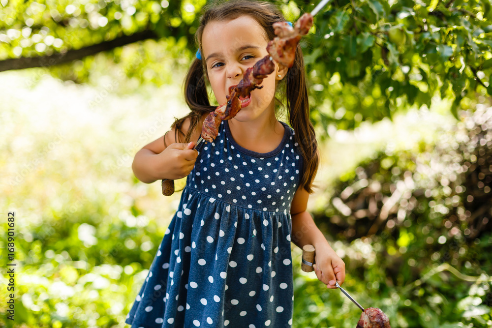 Little girl eating shish kebabs with skewers Stock Photo | Adobe Stock
