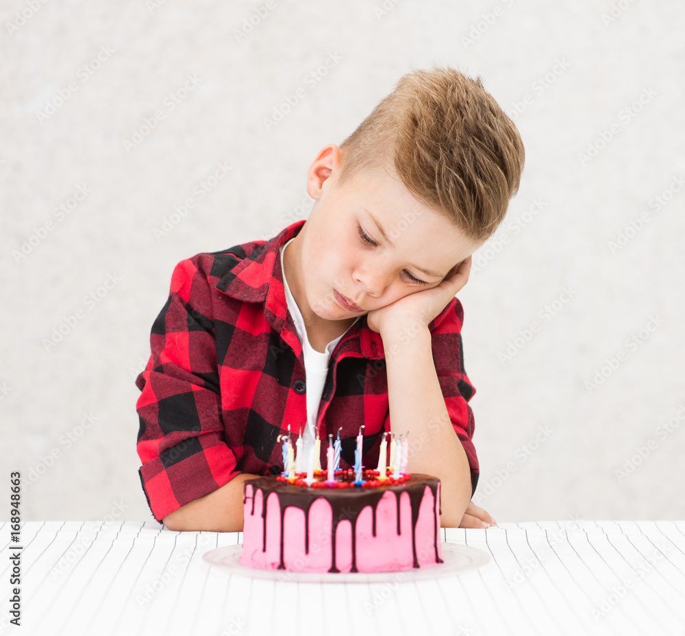 Sad boy sitting with cake with extinct candles Stock Photo | Adobe Stock
