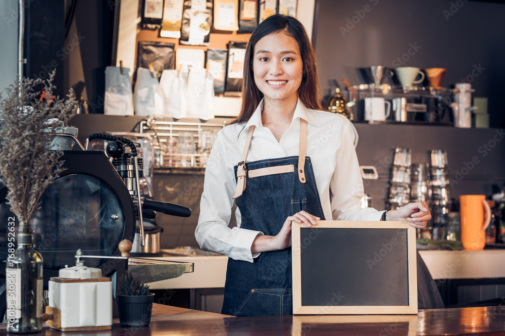 Asian female barista wear jean apron and holding blank blackboard menu ...
