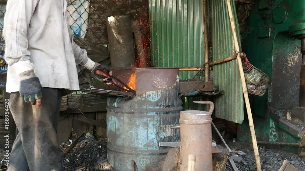 Blacksmith using a pair of pliers to heat a piece of metal inside a ...