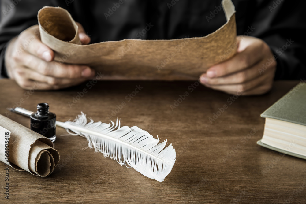 Man reading an old letter. Old quill pen, book and papyrus scroll on ...