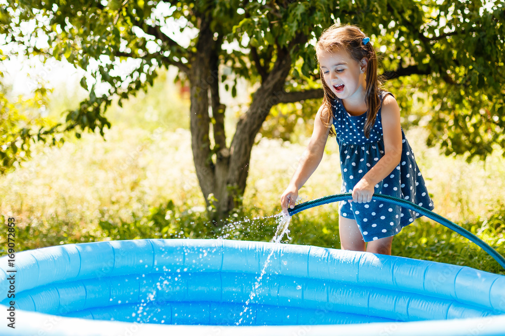 Little girl pouring water into a small pool Stock Photo | Adobe Stock