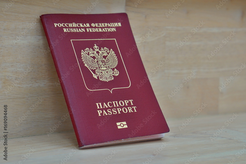 Red Russian passport on the wooden surface with captions Passport and ...
