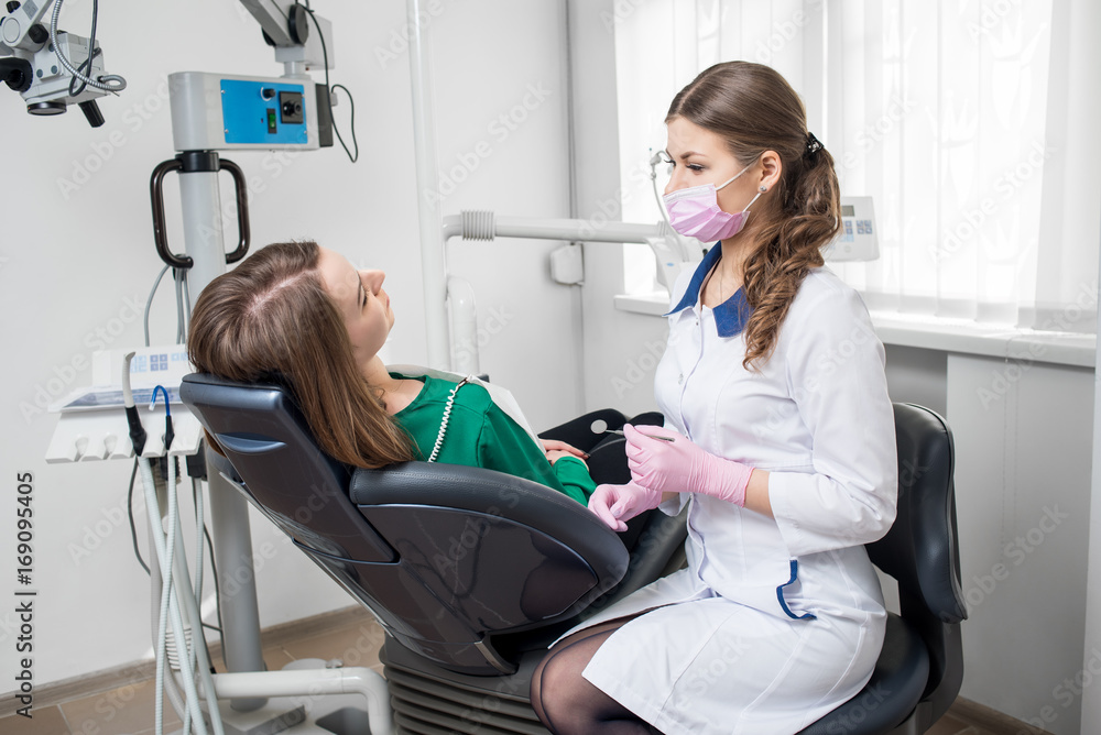Young female dentist with beautiful woman patient before dental ...