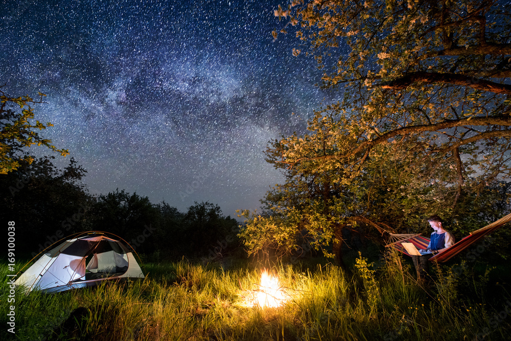 Female tourist using her laptop in the camping at night. Woman sitting ...