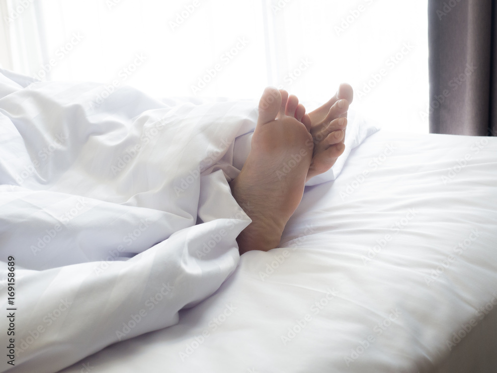 Feet of sleeping woman in white bed room.feet of a young woman lying in ...