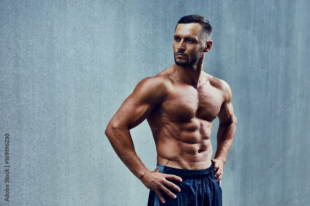 Portrait of an athletic man standing shirtless and looking away with ...