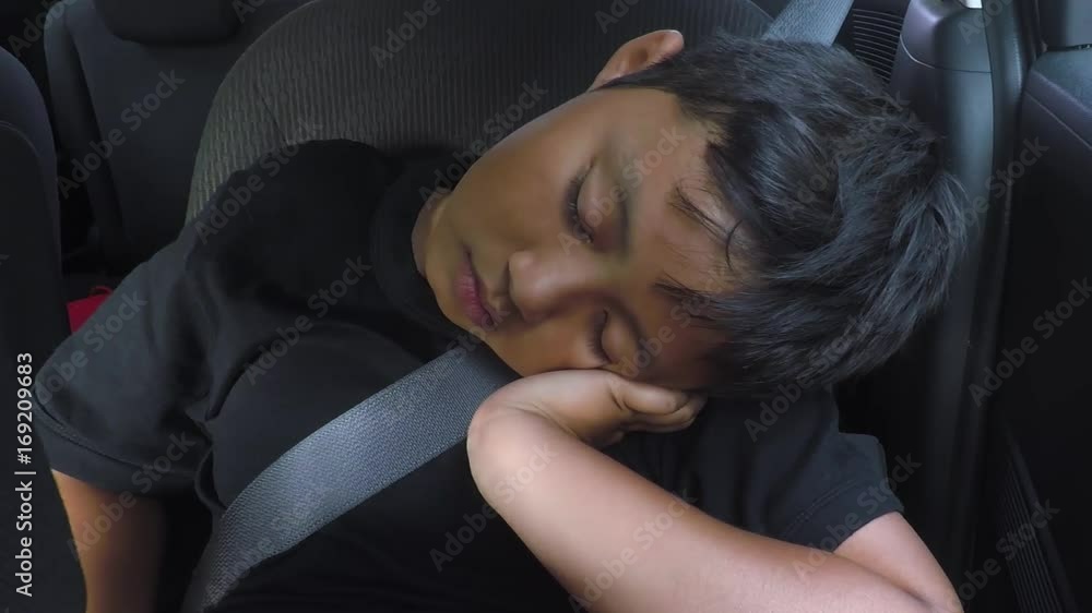 Video footage of a cute tired little boy sleeping inside a car while ...