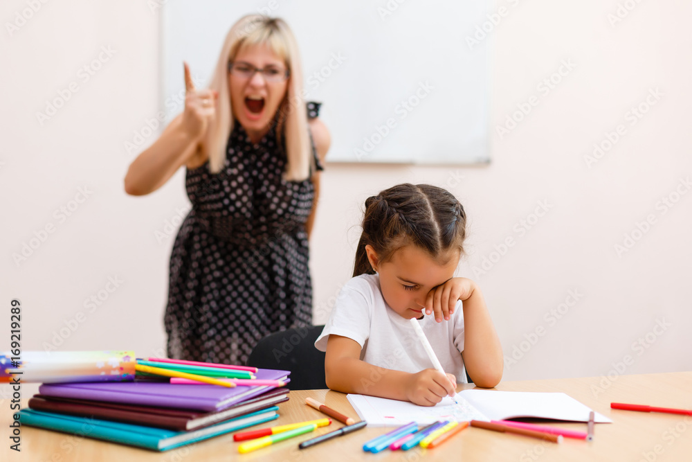the teacher screams at the little schoolgirl. Little girl is sad at the ...