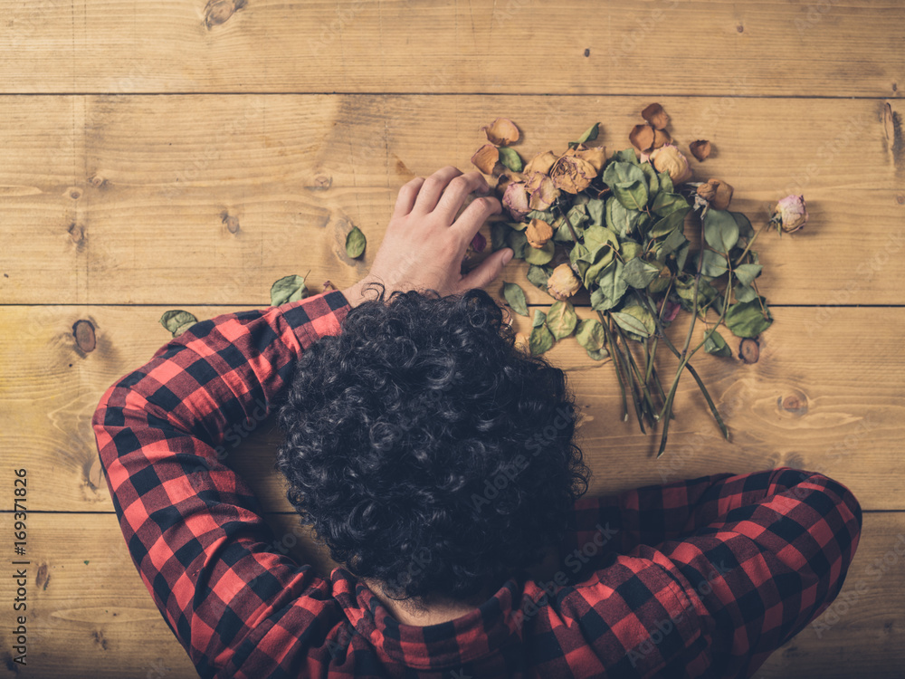 Sad man with dead flowers on the floor Stock Photo | Adobe Stock
