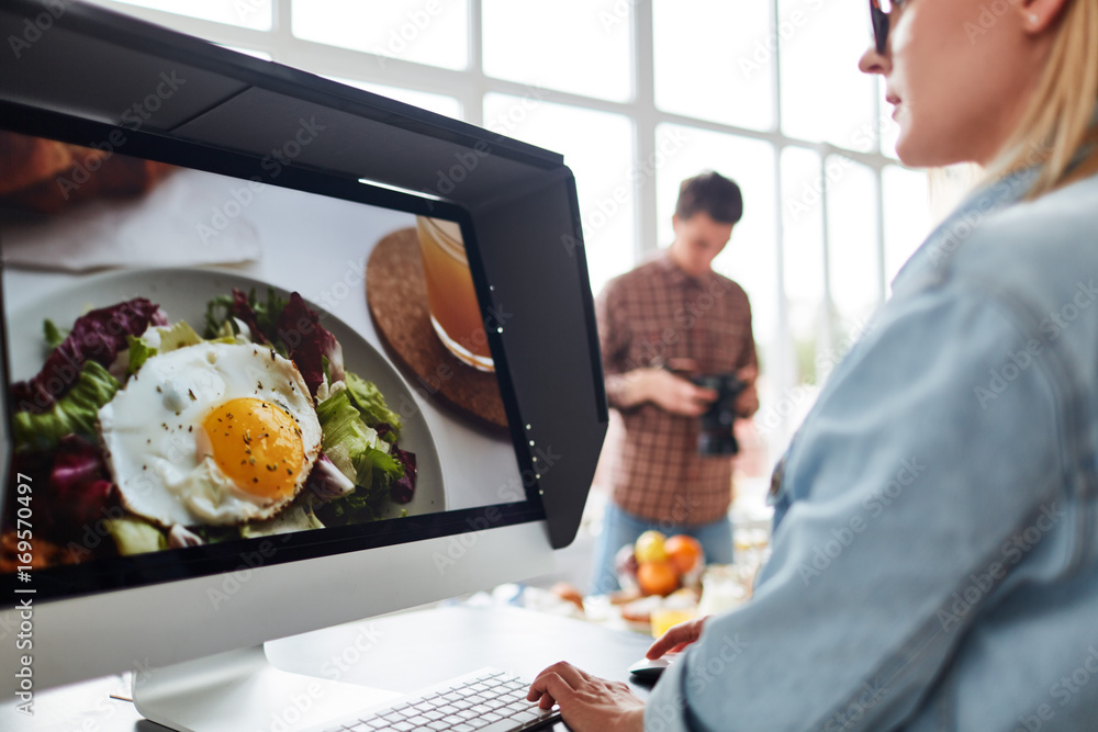 Professional food designer retouching photo while sitting in front of ...