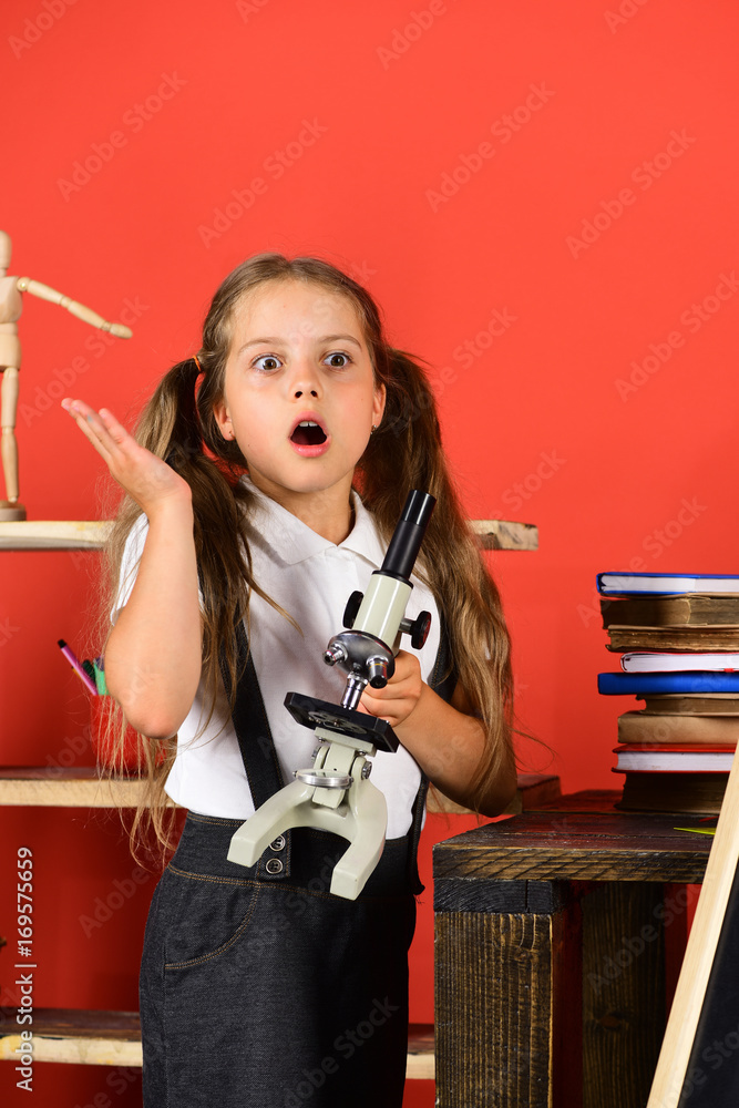 Schoolgirl with shocked face near bookshelf with school items Stock ...