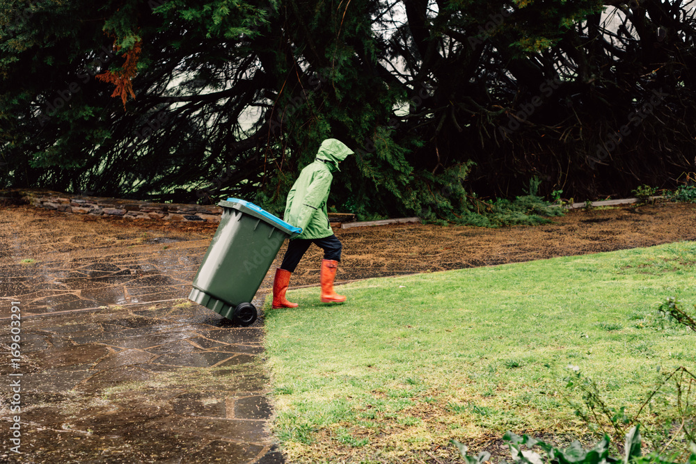 tween girl doing chores in the rain, taking the bin out Stock Photo ...
