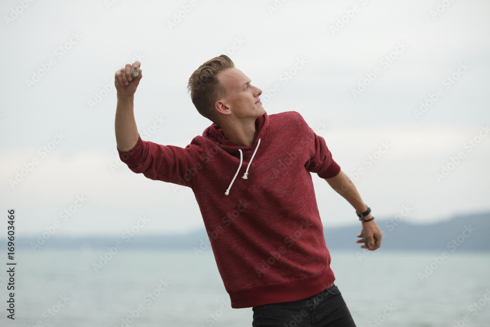 Blond man throwing stone in river Stock Photo | Adobe Stock