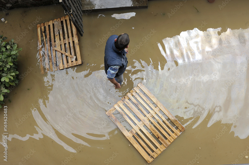 The consequences of flooding, man in the water helping neighborhood ...