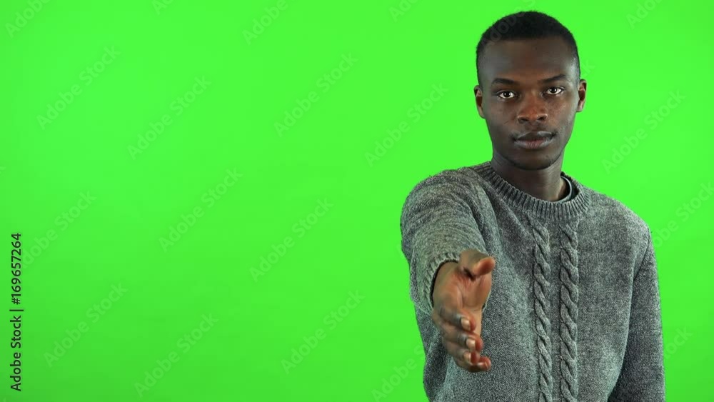 A young black man extends his arm to the camera for a handshake - green ...