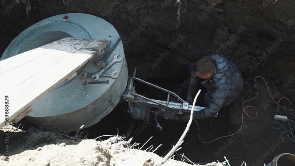 Man drilling big circular hole in a concrete chamber manhole ring in ...