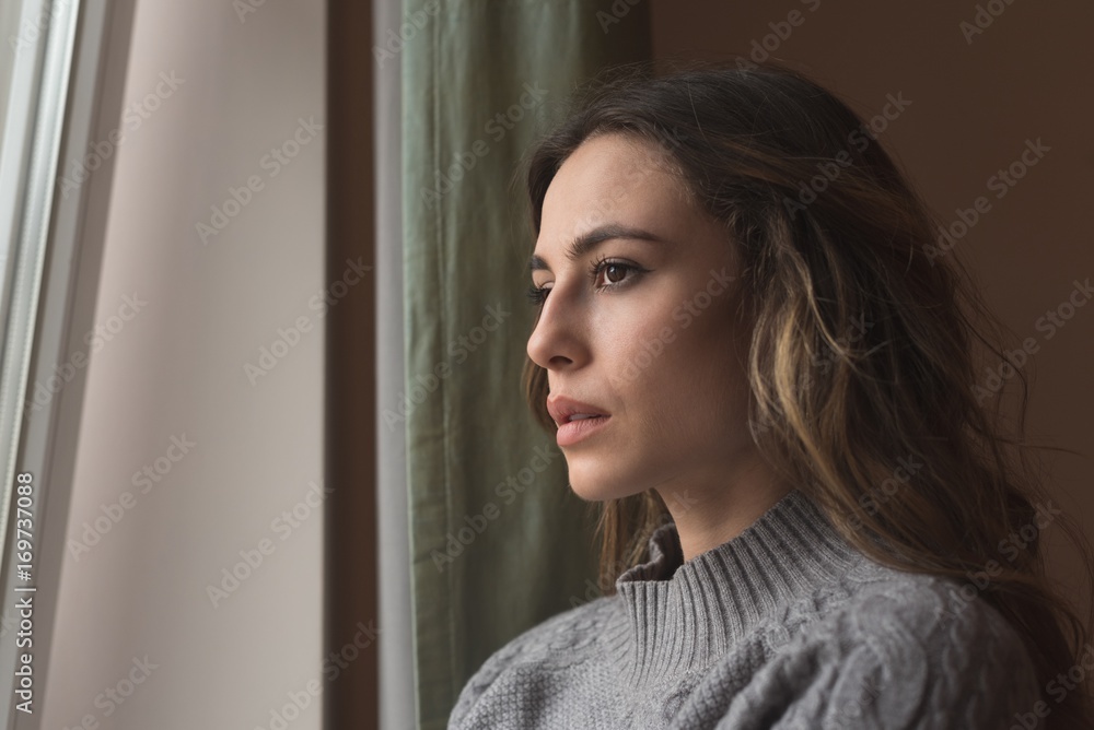 Thoughtful woman looking through window Stock Photo | Adobe Stock