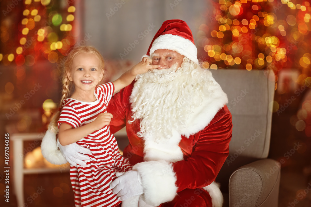 Cute little girl sitting on Santa's lap in room with beautiful ...