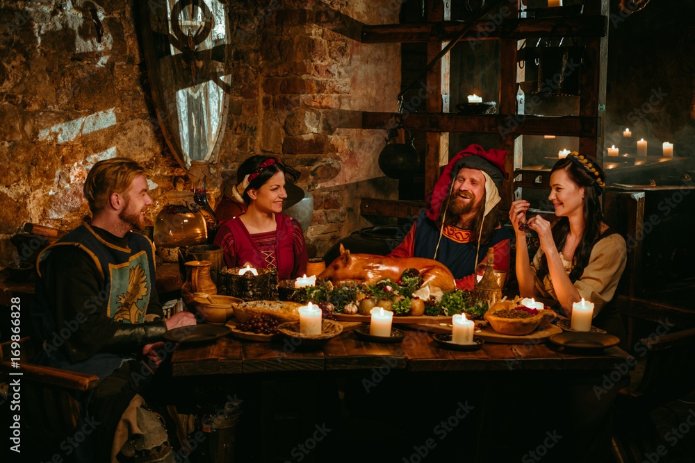 Medieval people eat and drink in castle tavern. Stock Photo | Adobe Stock