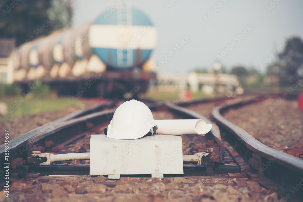 White helmet With the project plan on the railroad tracks with ...