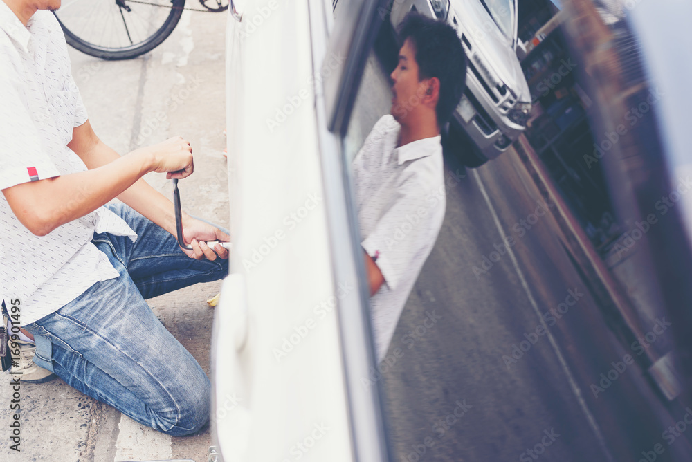 Young man changing flat tire on the road .Replacing the tires on the ...