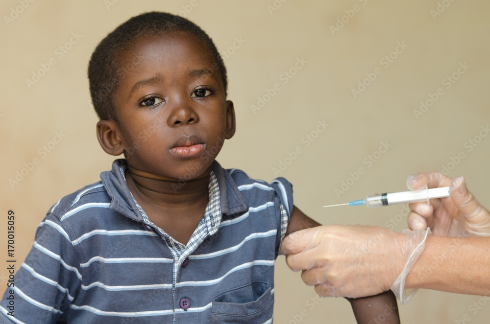 White doctor giving black African boy a needle injection as a ...