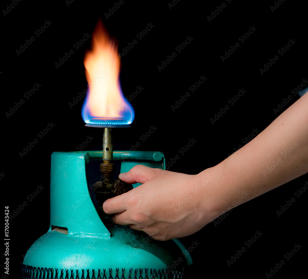Male hand turning gas stove on a black background,operating valve of ...