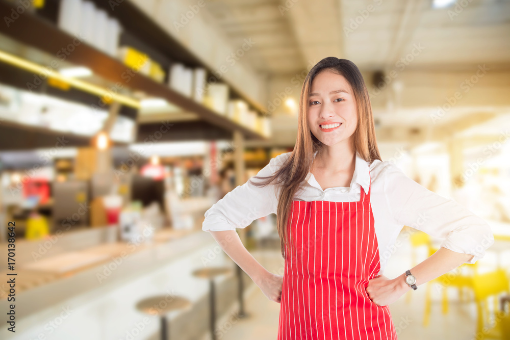 Beautiful asian woman wearing red apron looking at camera and smiles ...