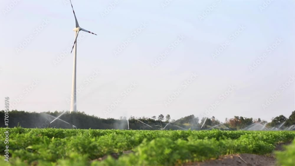 Wind mill turbine at field with automatic irrigation system background ...