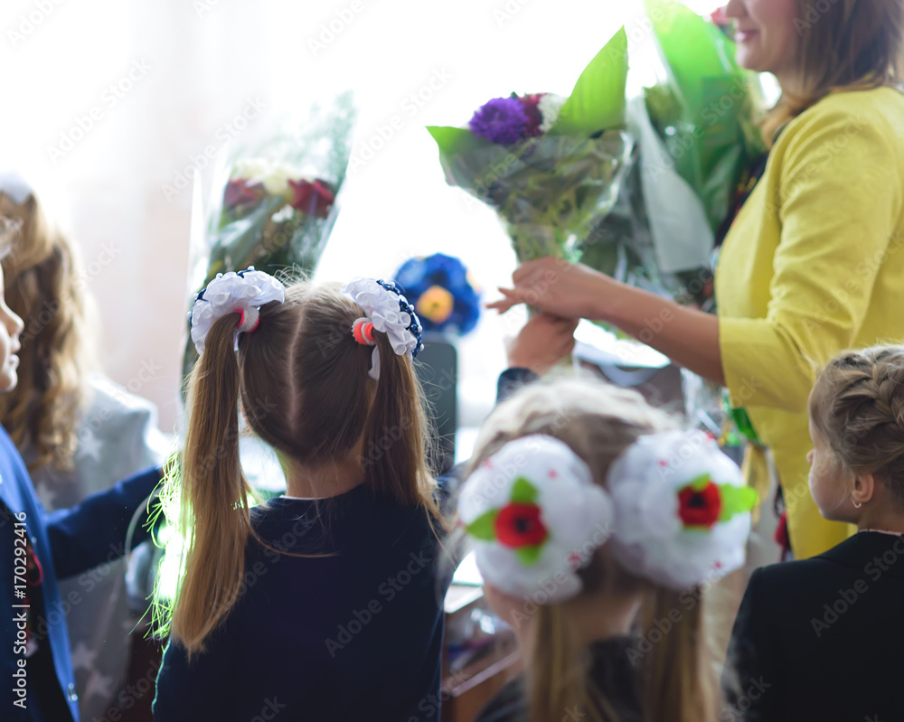 Children give flowers to a woman teacher Stock Photo | Adobe Stock