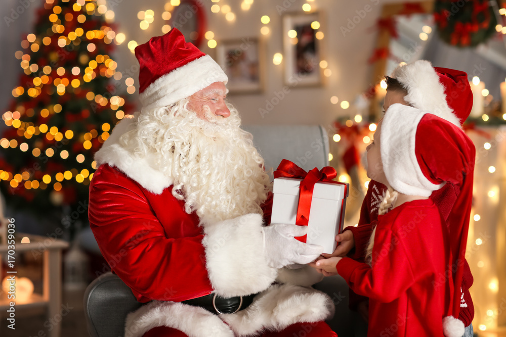 Santa Claus giving present to children in room with beautiful Christmas ...