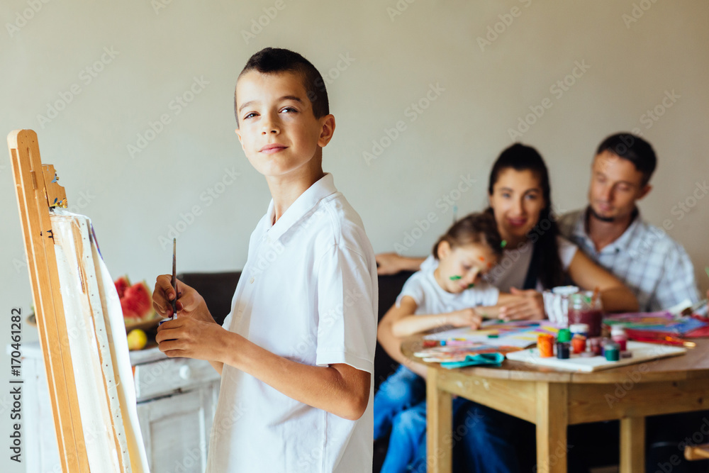 Teeneger boy painting with easel, his sister, mother and father drawing ...