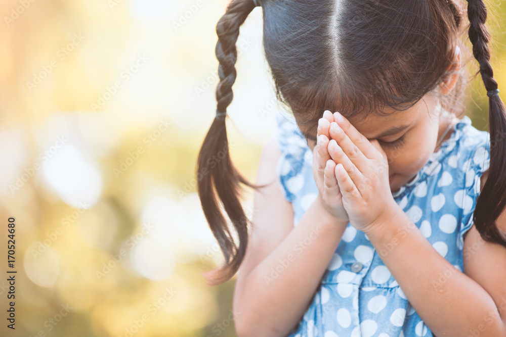 Cute asian little child girl praying with folded her hand for faith ...