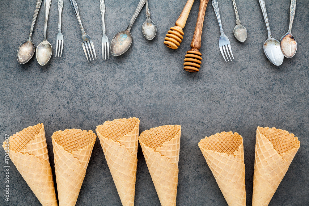 Flat lay ice cream cones collection , spoons ,fork and honey dipper on dark stone background ...