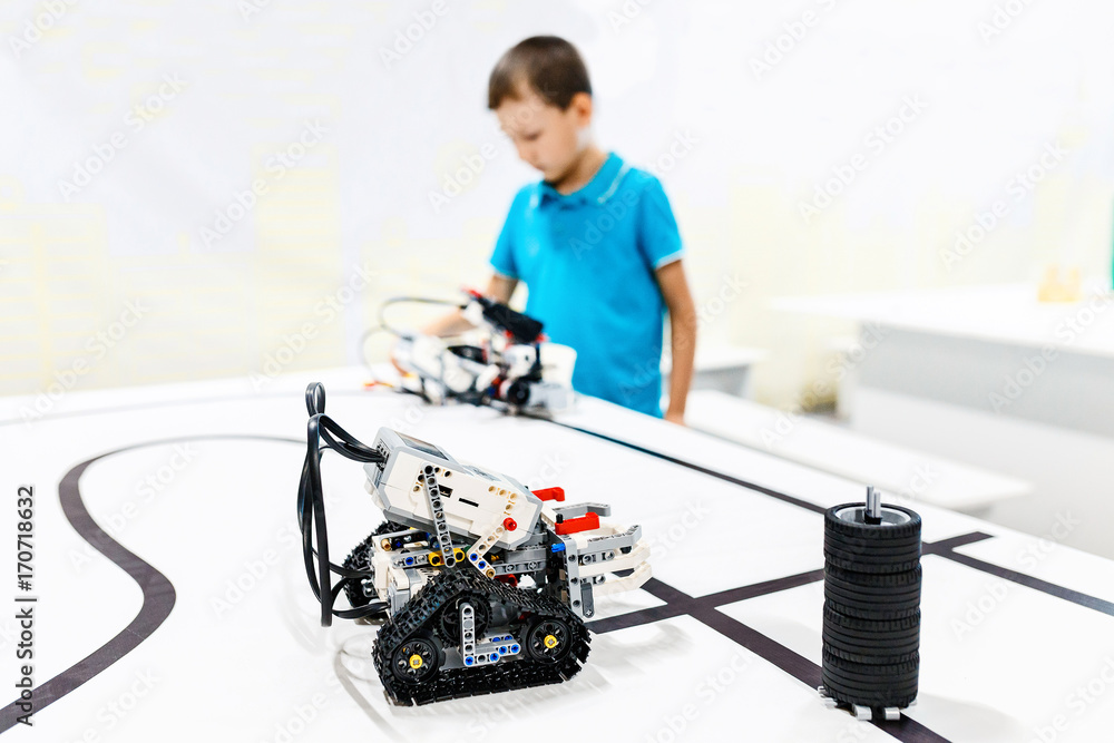 Genius kid working and playing with selfmade robots and ...