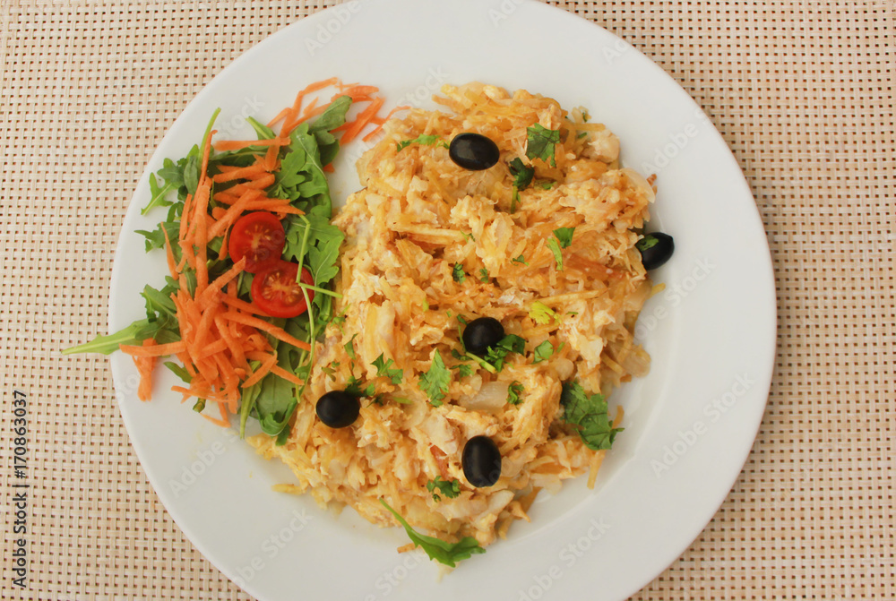 Dried and salted codfish cooked with eggs, potato chips and olives ...
