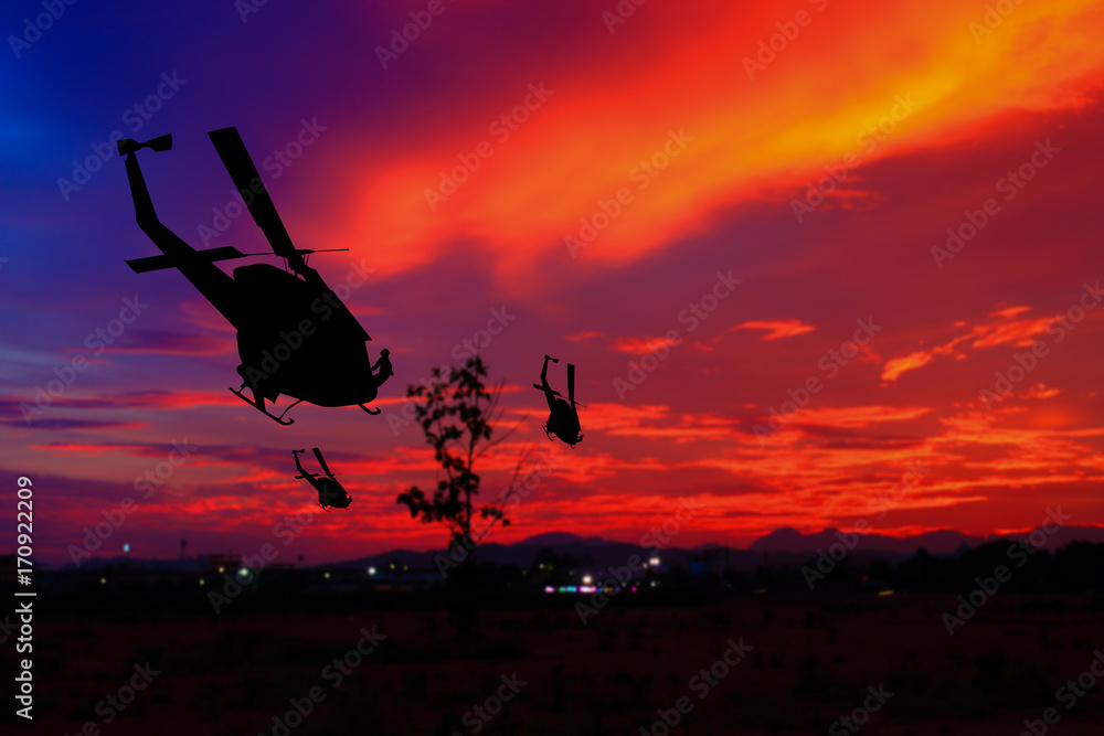soldier silhouette in rappelling climb down from helicopter on sunset ...
