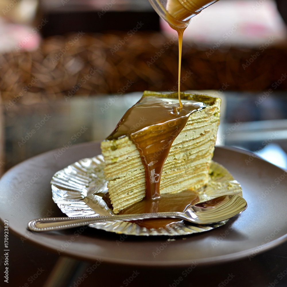 Pouring caramel sweet sauce to delicious green tea crepe Cake.Homemade ...