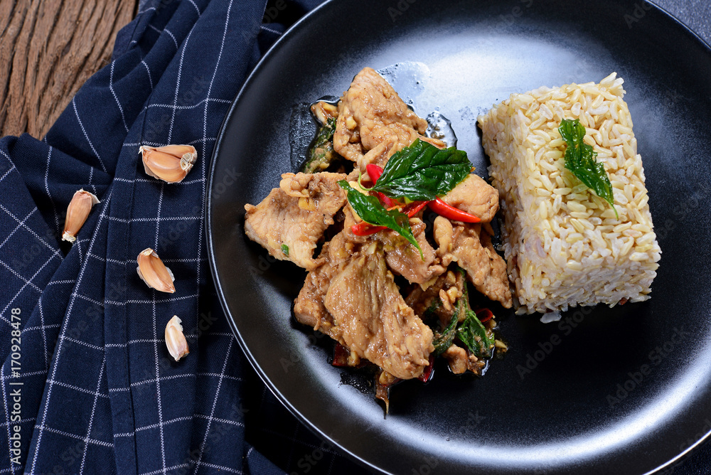 Top view of stir-fried chicken with basil and rice on black background ...